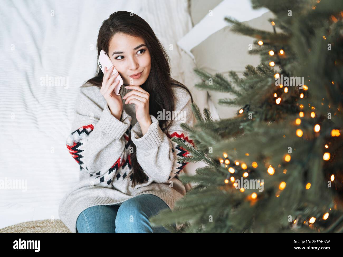 Young beautiful asian woman with dark long hair in cozy sweater using ...