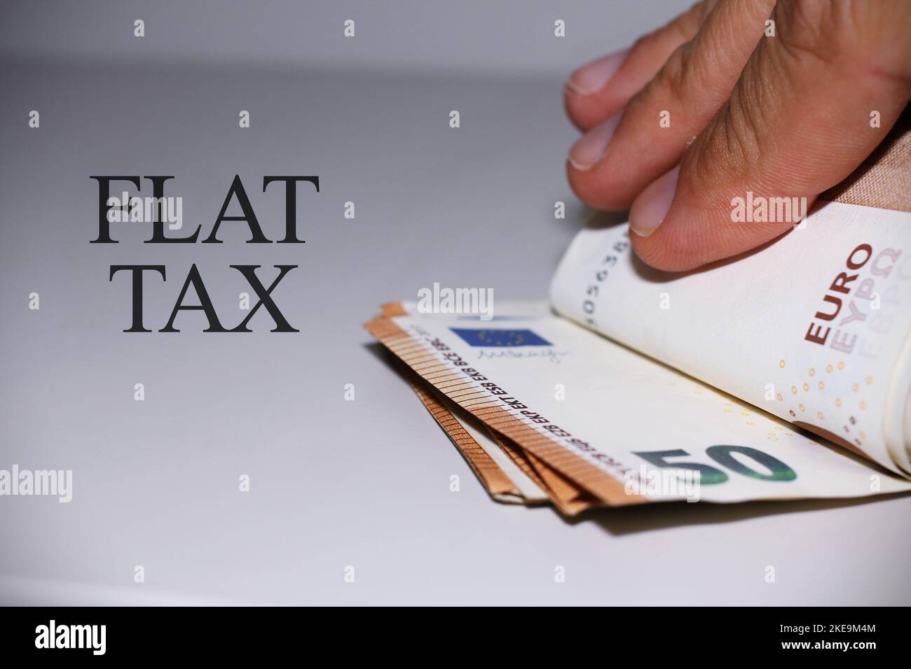Shot of a hand with money on the table with the text "Flat Tax Stock ...