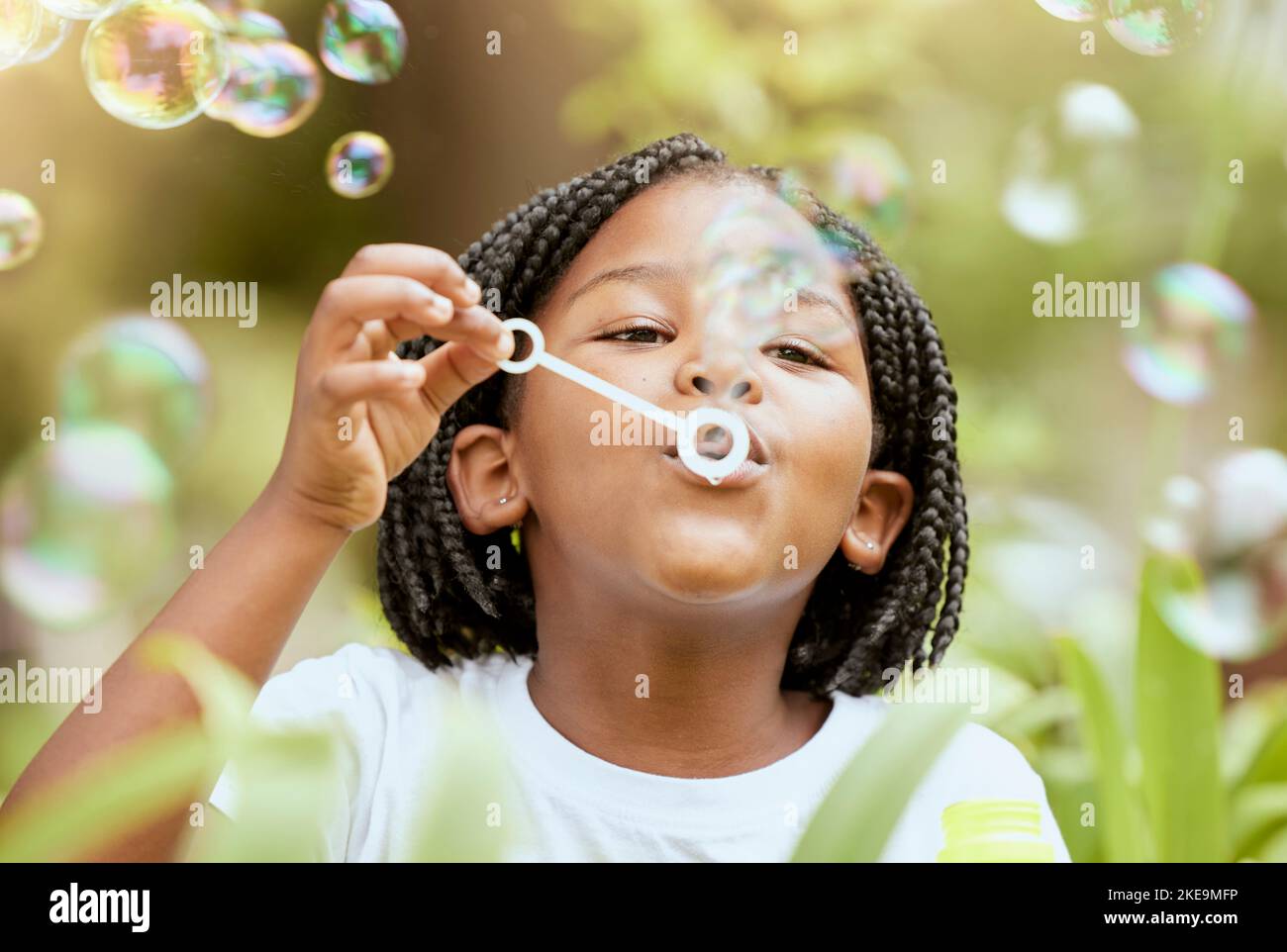 Bubbles, playful and African girl in nature with freedom, smile and ...