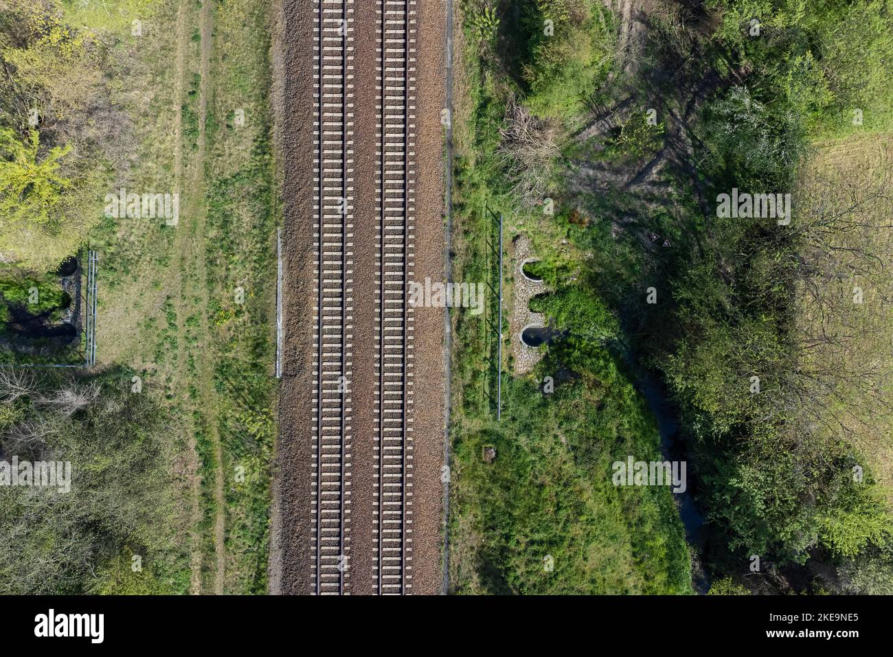 An aerial shot of empty parallel railways surrounded by grass in the ...