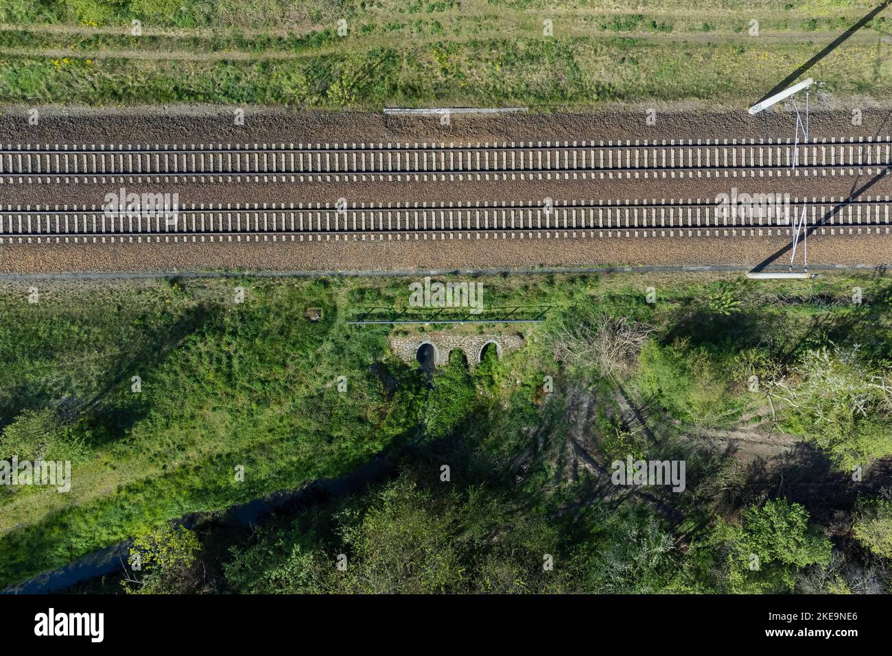 An aerial shot of empty parallel railways surrounded by grass in the ...