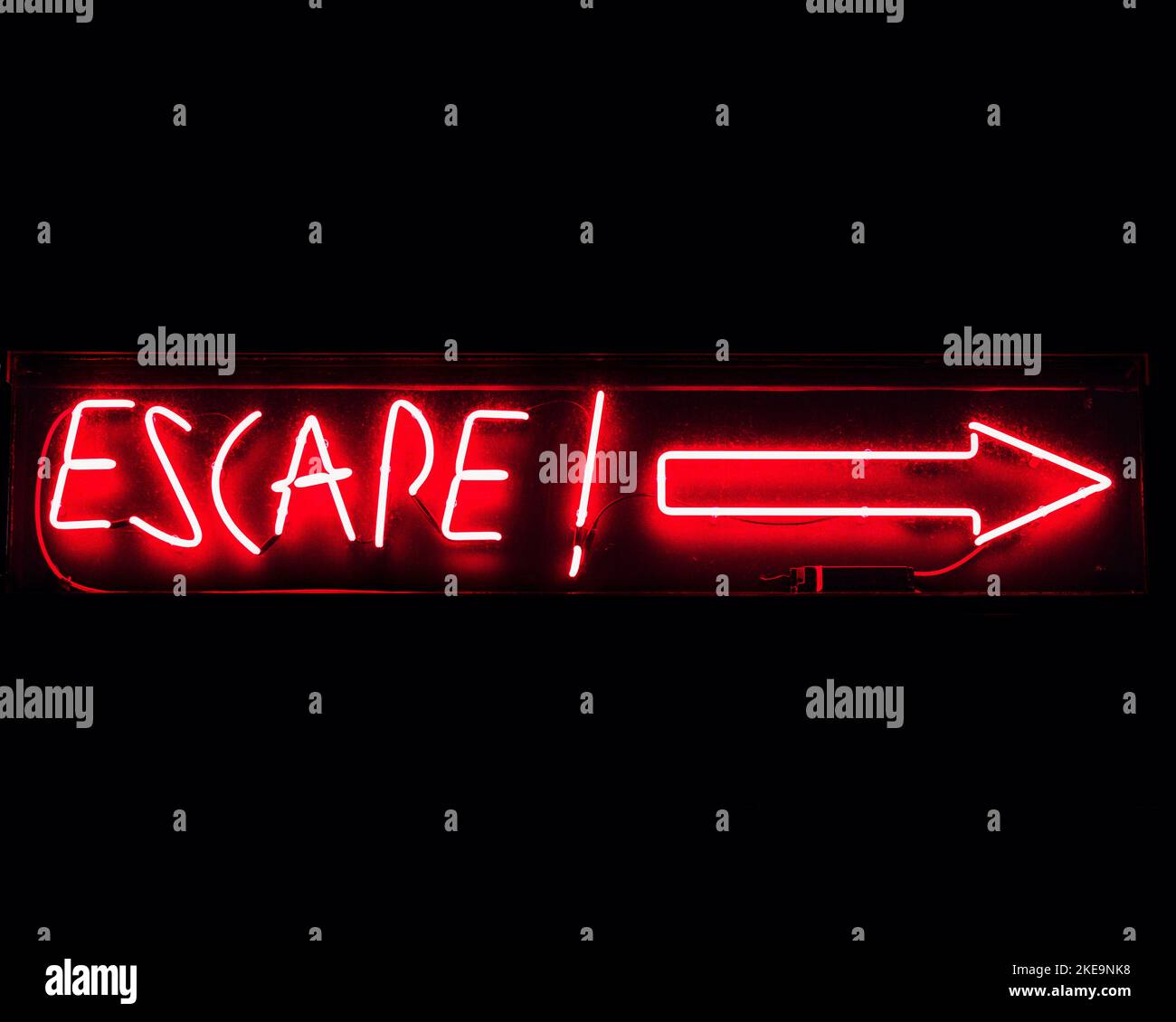 An Escape neon sign in red with arrow pointing right on black ...