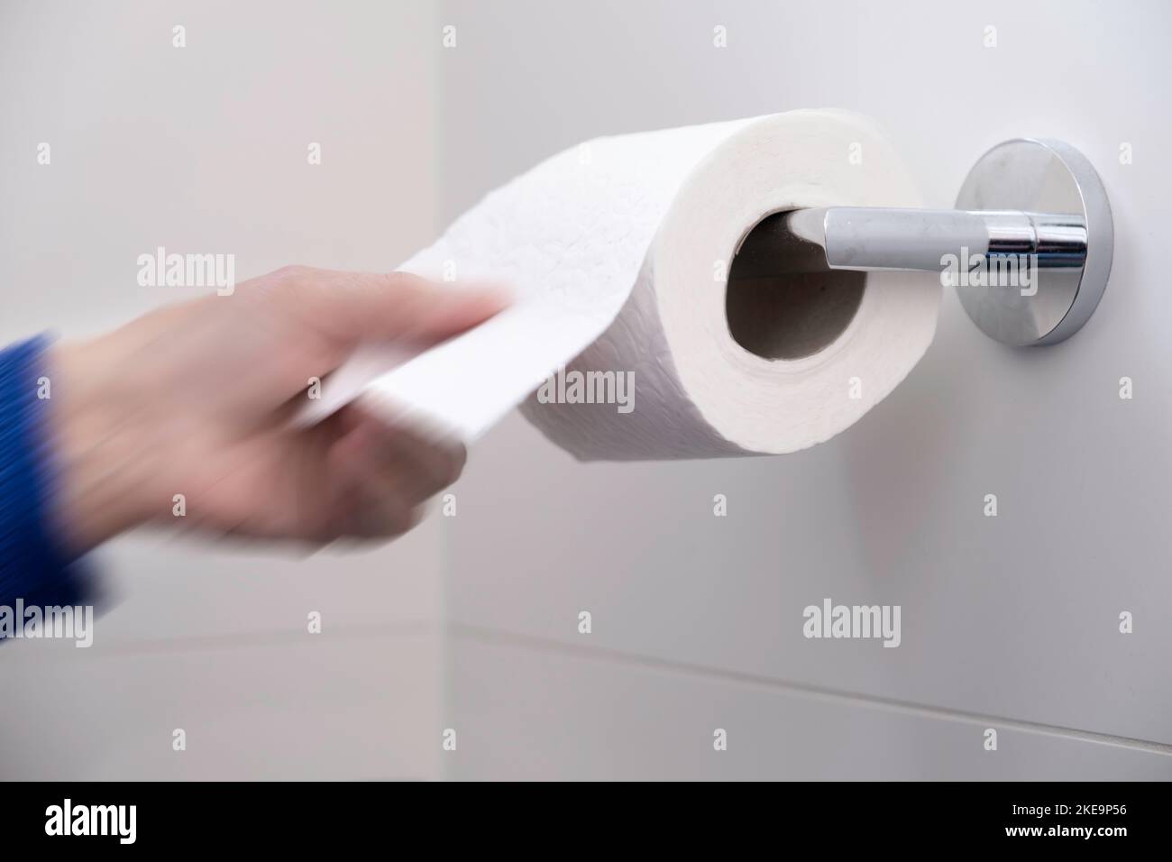 Hand tears a sheet of paper from a toilet paper roll. Motion blur of ...