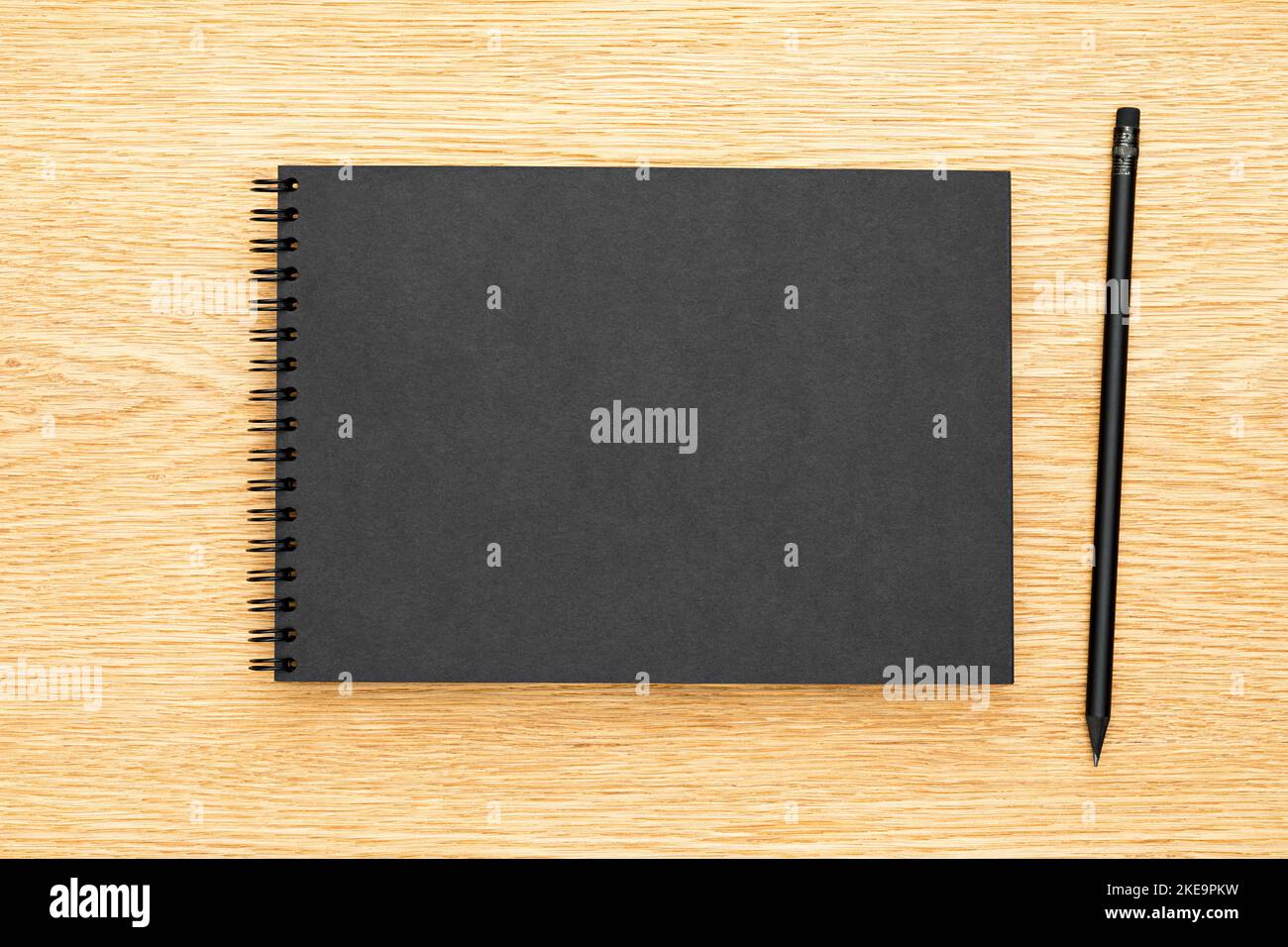 Black paper notebook on oak wood desk background Stock Photo - Alamy