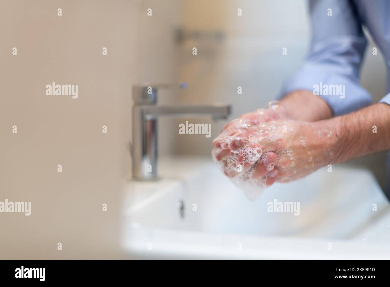 Man using soap and washing hands under the water tap. Hygiene concept ...