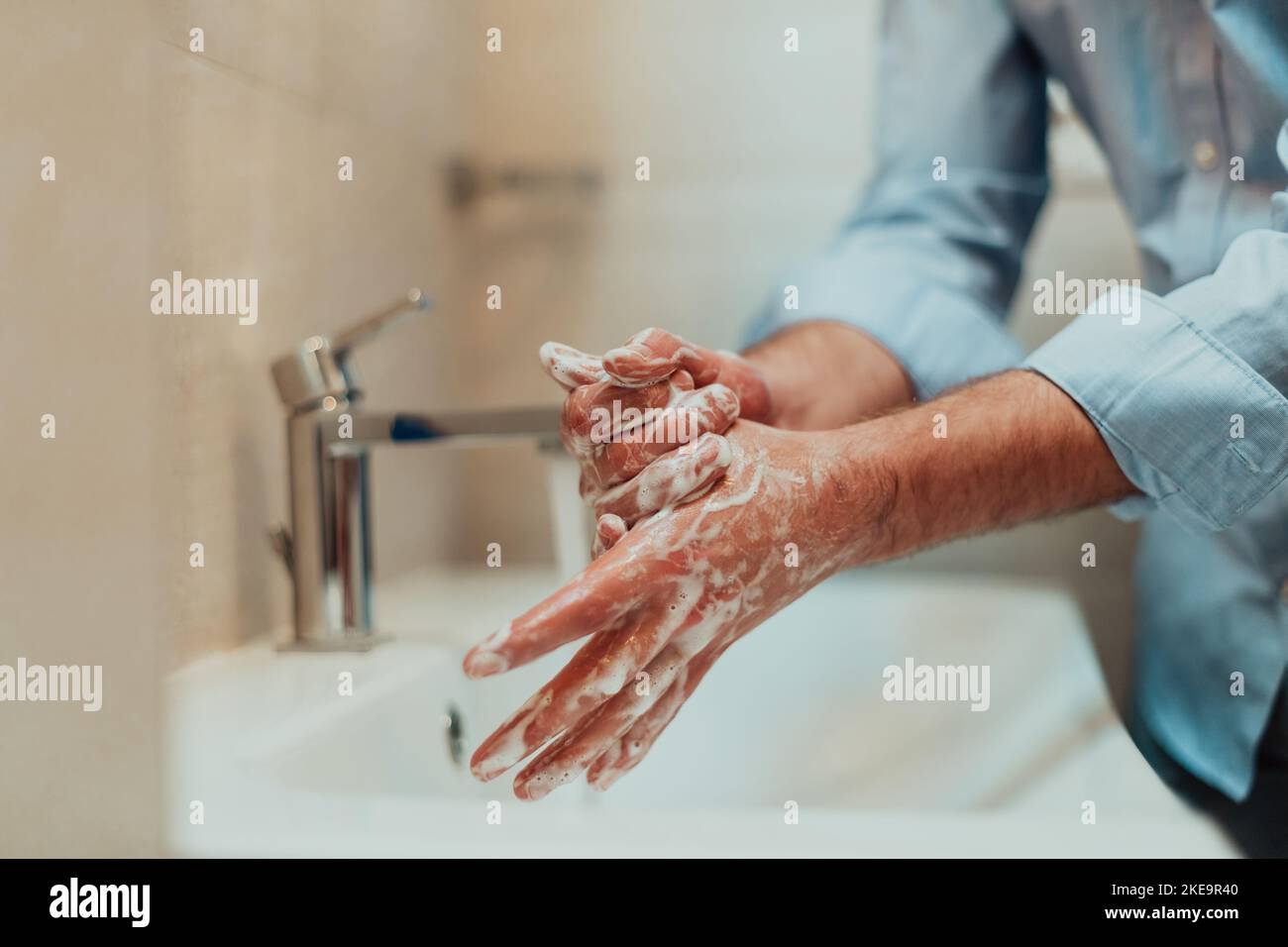 Man using soap and washing hands under the water tap. Hygiene concept ...