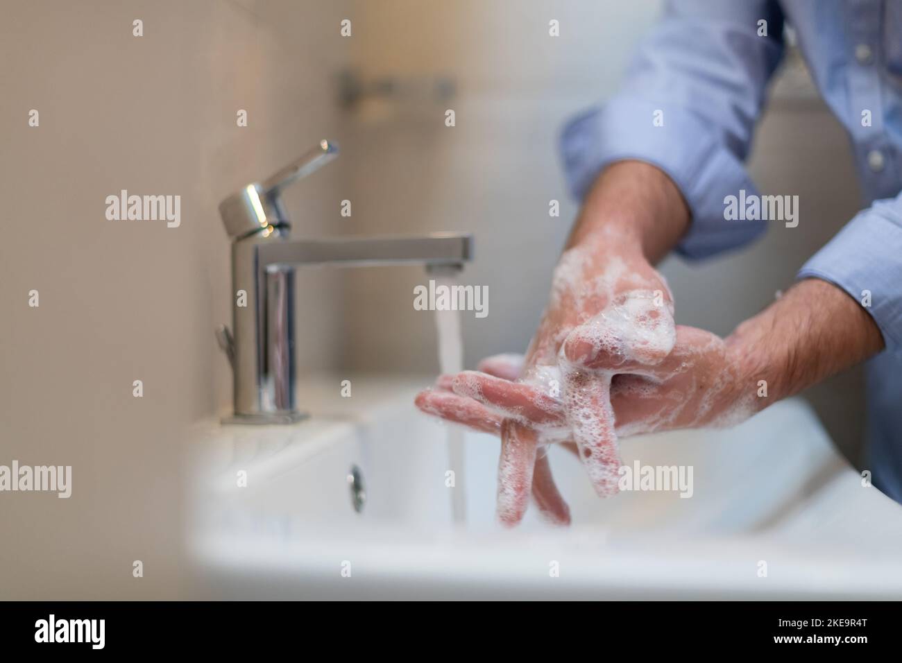 Man using soap and washing hands under the water tap. Hygiene concept ...