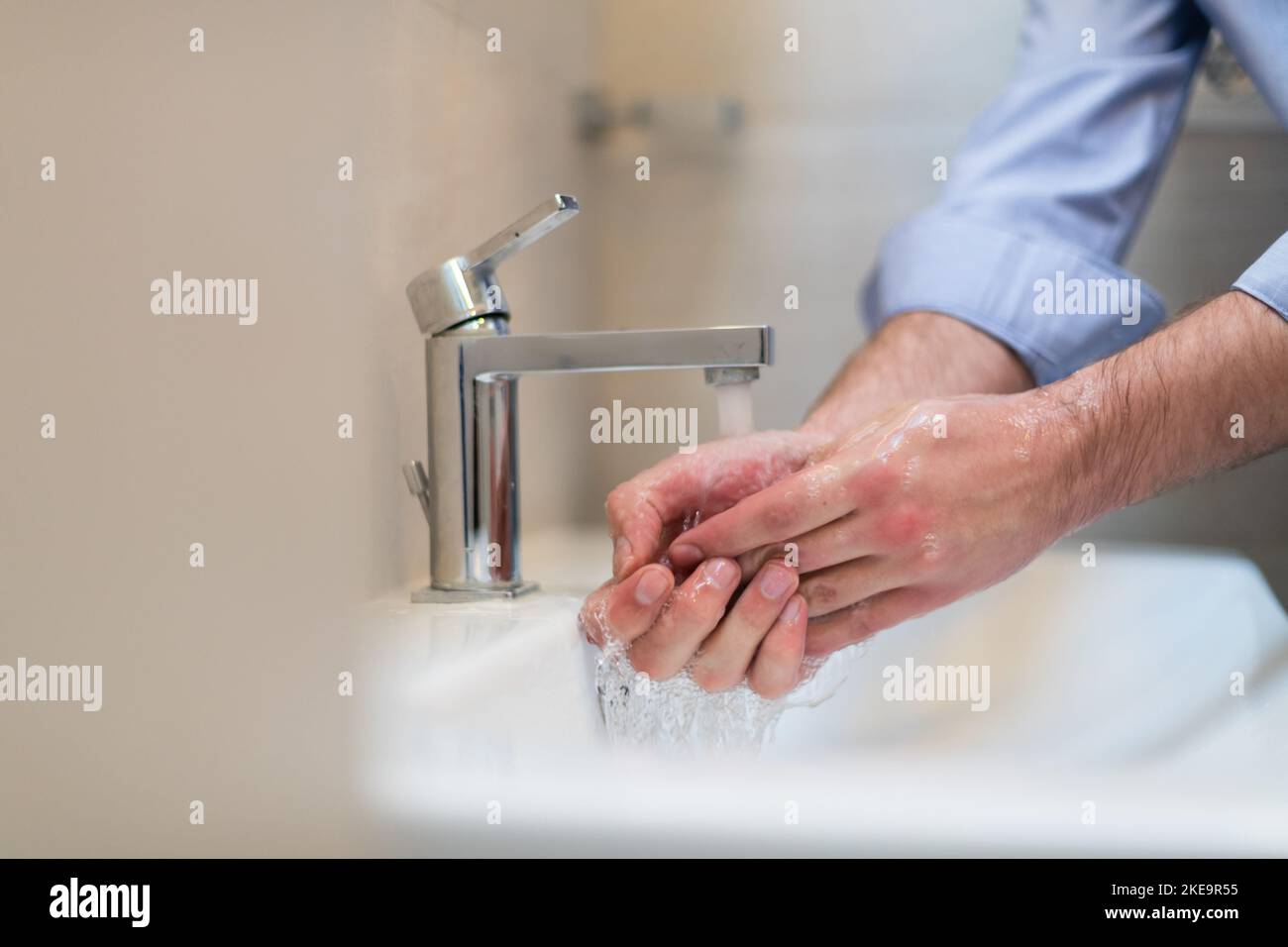 Man using soap and washing hands under the water tap. Hygiene concept ...
