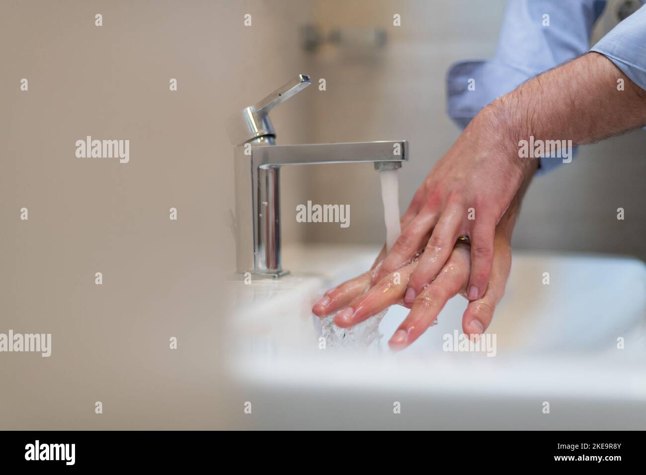 Man using soap and washing hands under the water tap. Hygiene concept ...