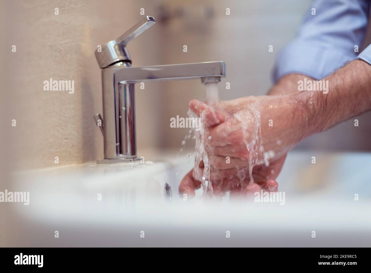 Man using soap and washing hands under the water tap. Hygiene concept ...