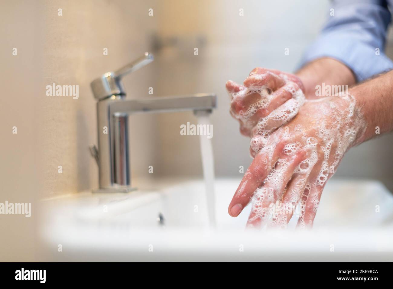 Man using soap and washing hands under the water tap. Hygiene concept ...