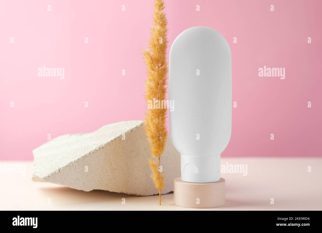 Empty white plastic tube on a round plaster podium. Natural cosmetics ...