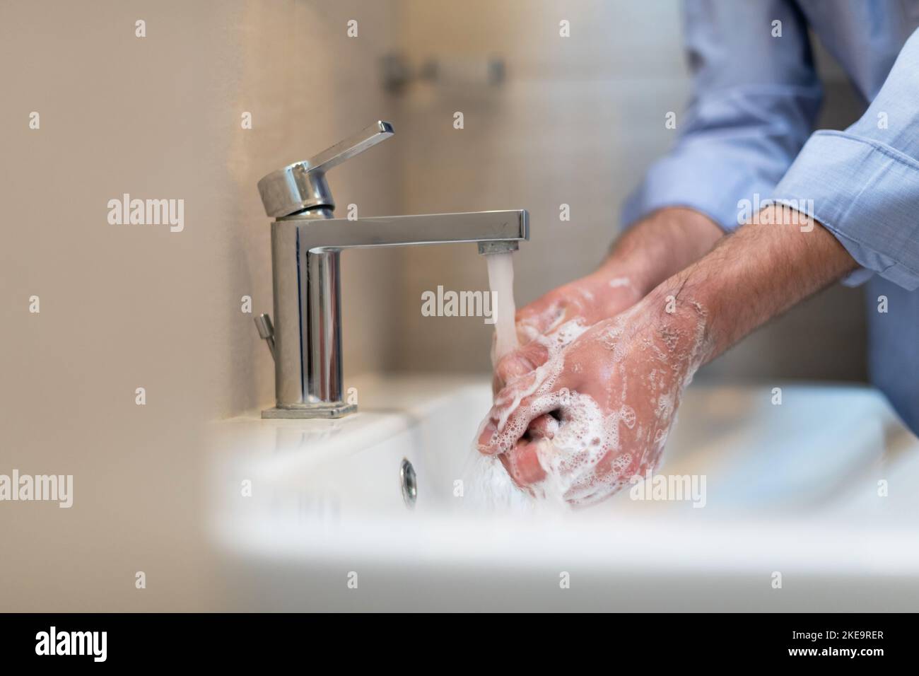 Man using soap and washing hands under the water tap. Hygiene concept ...