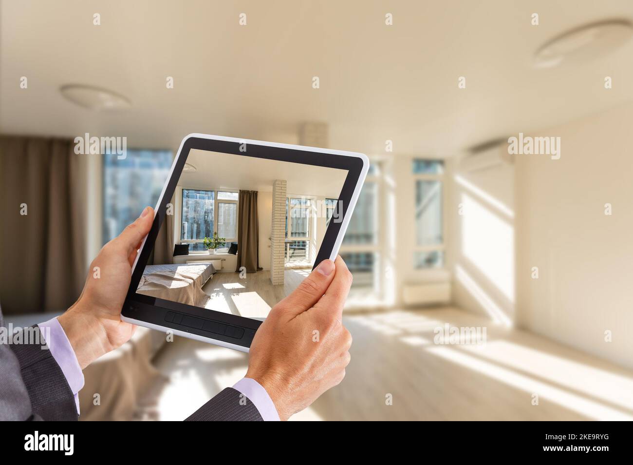 Hands holding tablet showing plans in finished room. Modern apartment ...