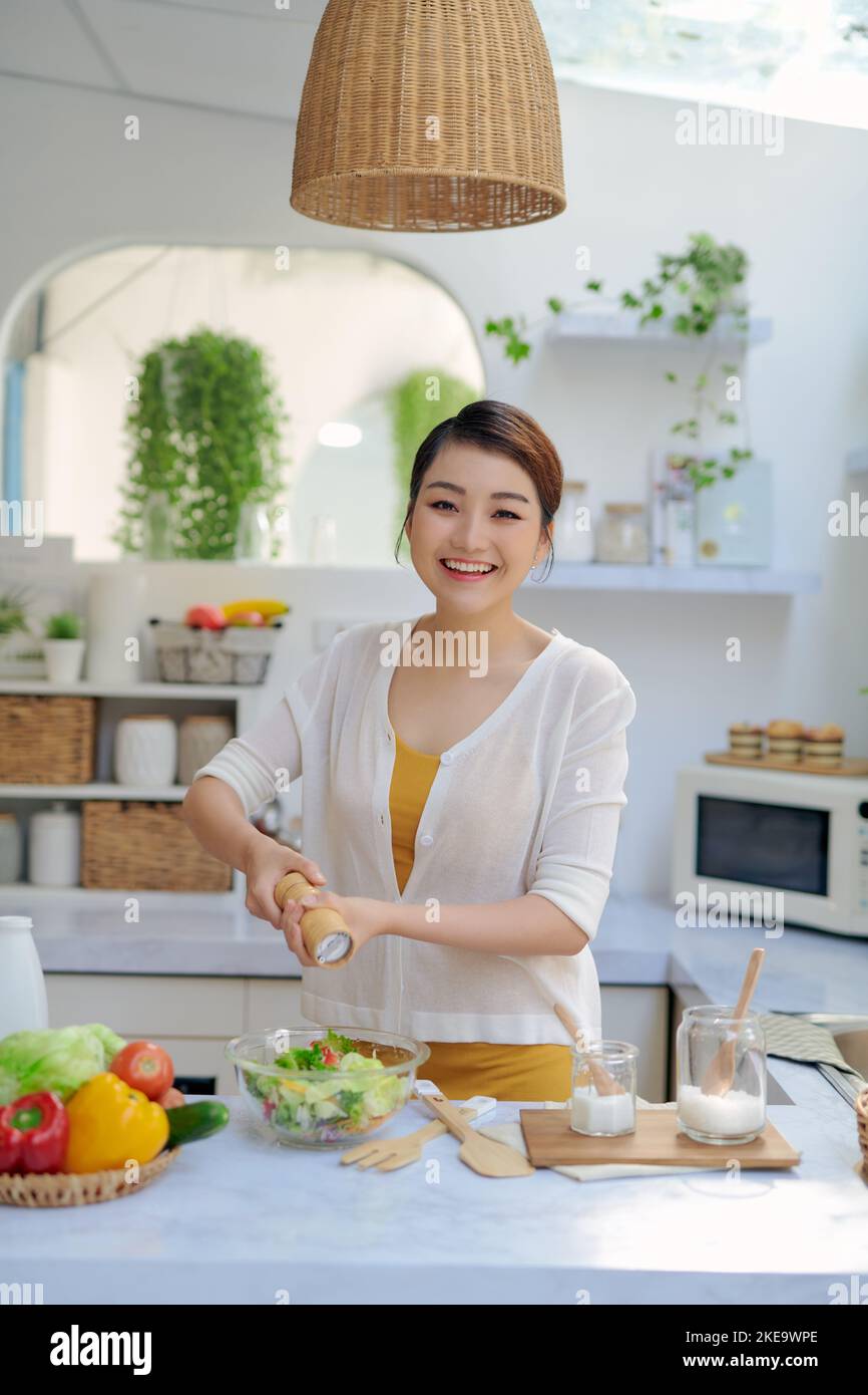 Pretty young woman chef putting salt in a salad Stock Photo - Alamy