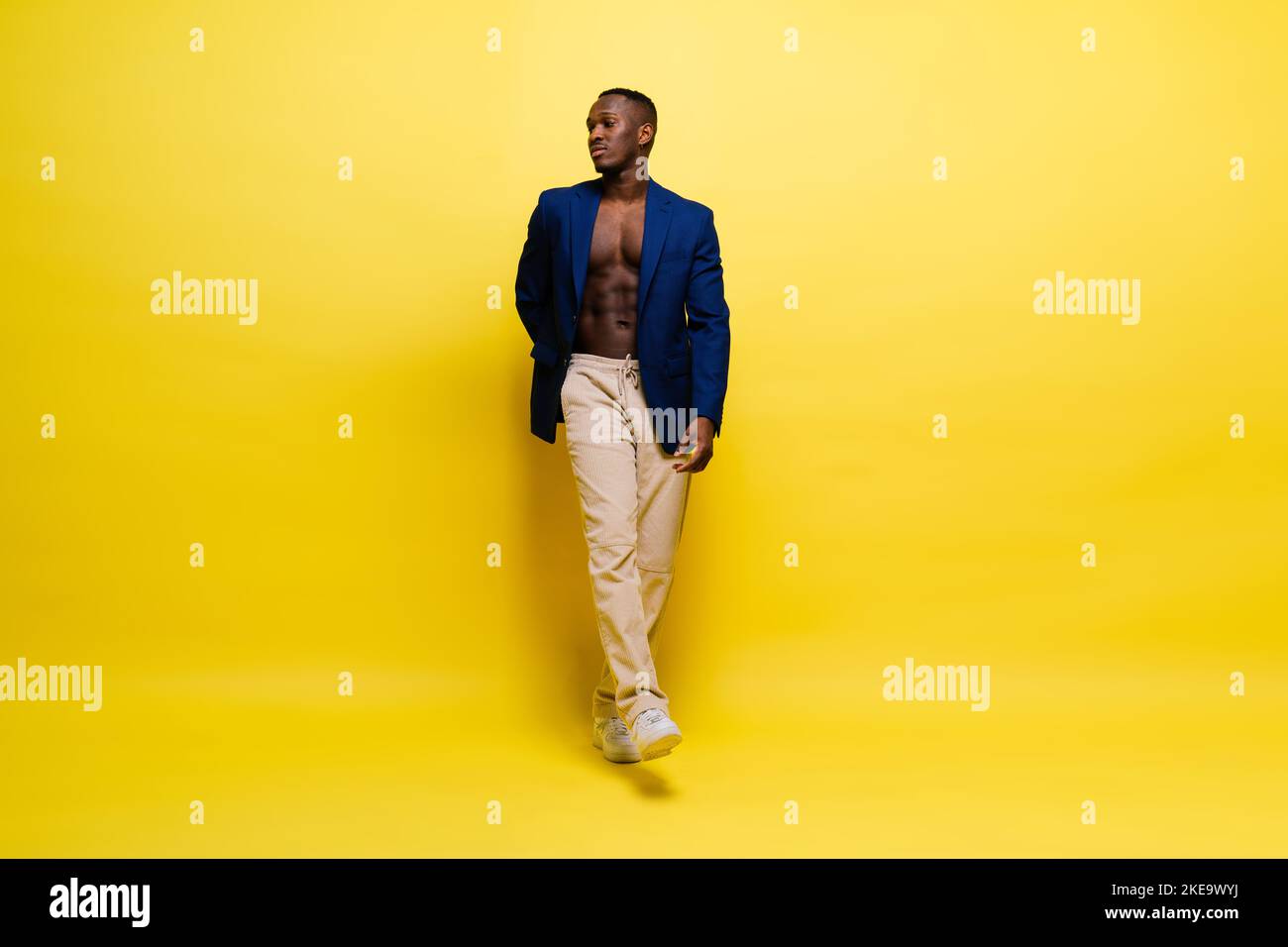 Guy in blue suit on yellow background. Handsome athletic man in jacket ...