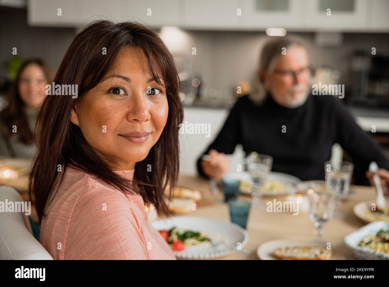 Portrait of woman having dinner with family Stock Photo - Alamy