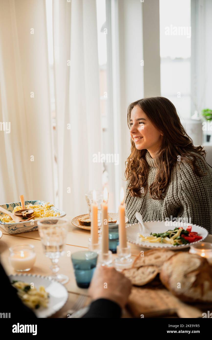 Smiling teenage girl sitting at dinner table Stock Photo - Alamy