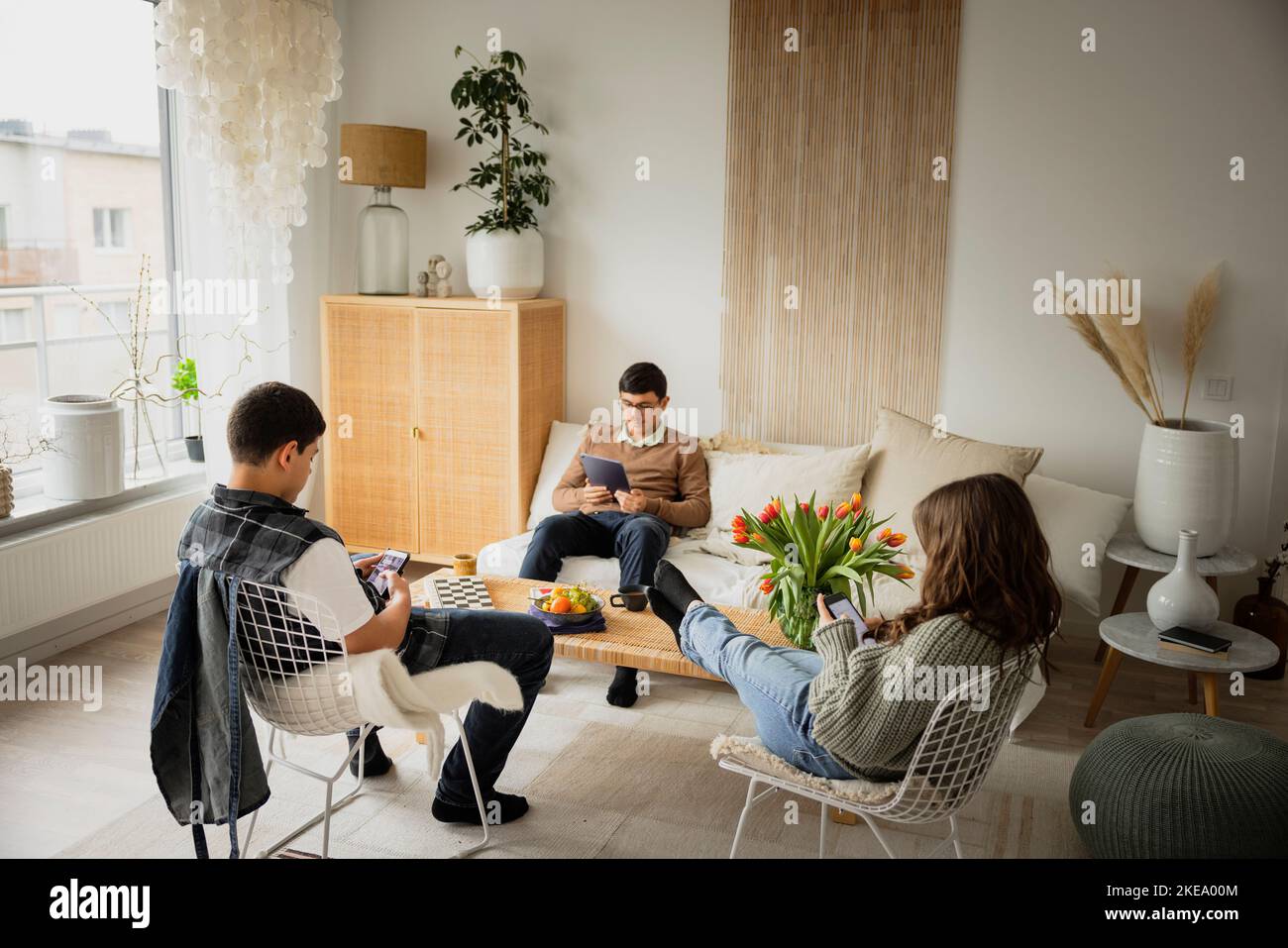 Siblings using phones and tablet at home Stock Photo - Alamy