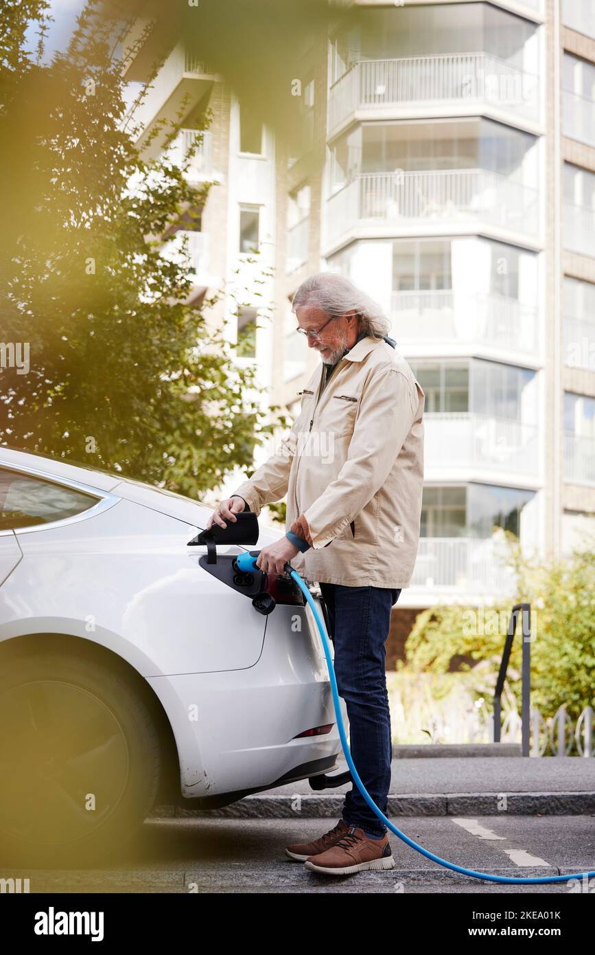 Senior man charging electric car Stock Photo - Alamy