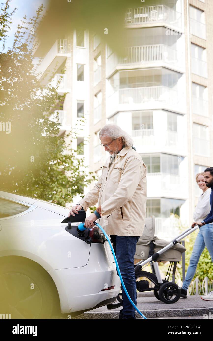 Senior man charging electric car Stock Photo - Alamy