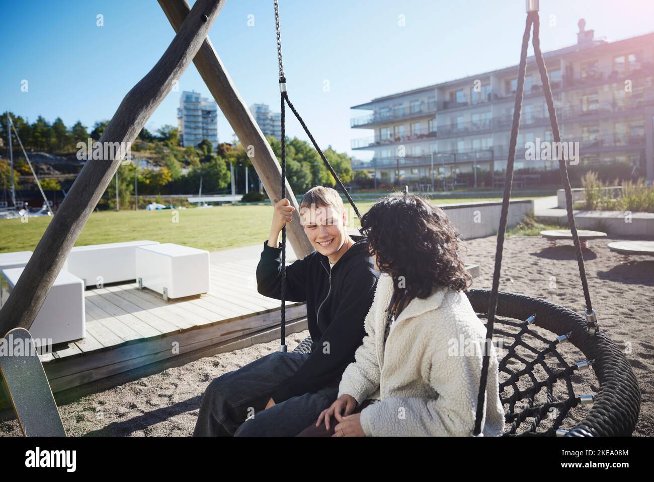 Friends sitting on swing Stock Photo - Alamy