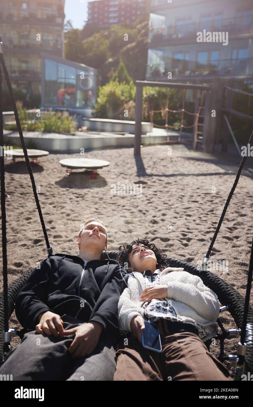 Friends relaxing on swing Stock Photo - Alamy