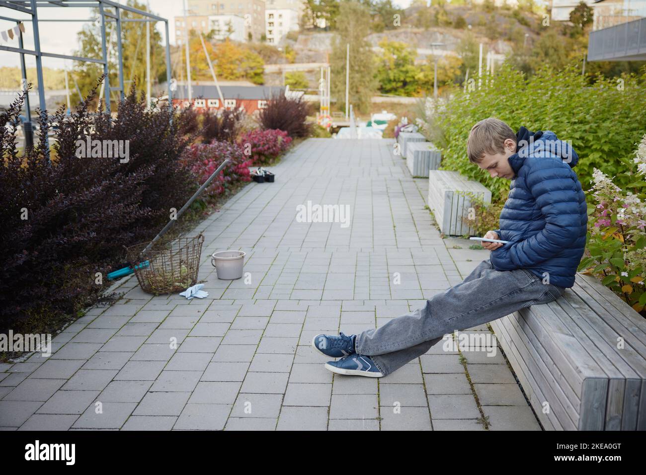 Teenage boy sitting on bench and using phone Stock Photo - Alamy