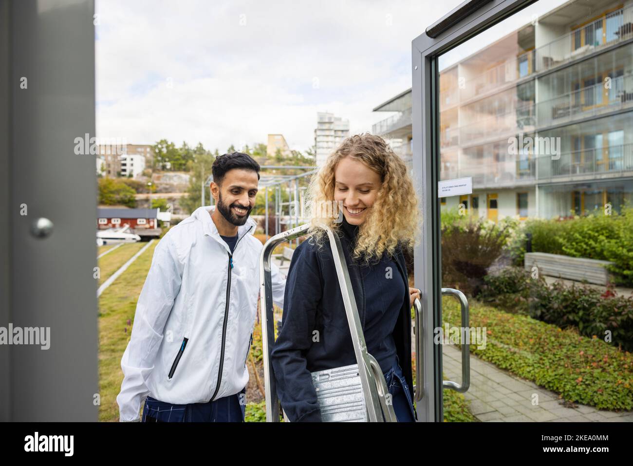 Young technicians entering building with ladder Stock Photo - Alamy