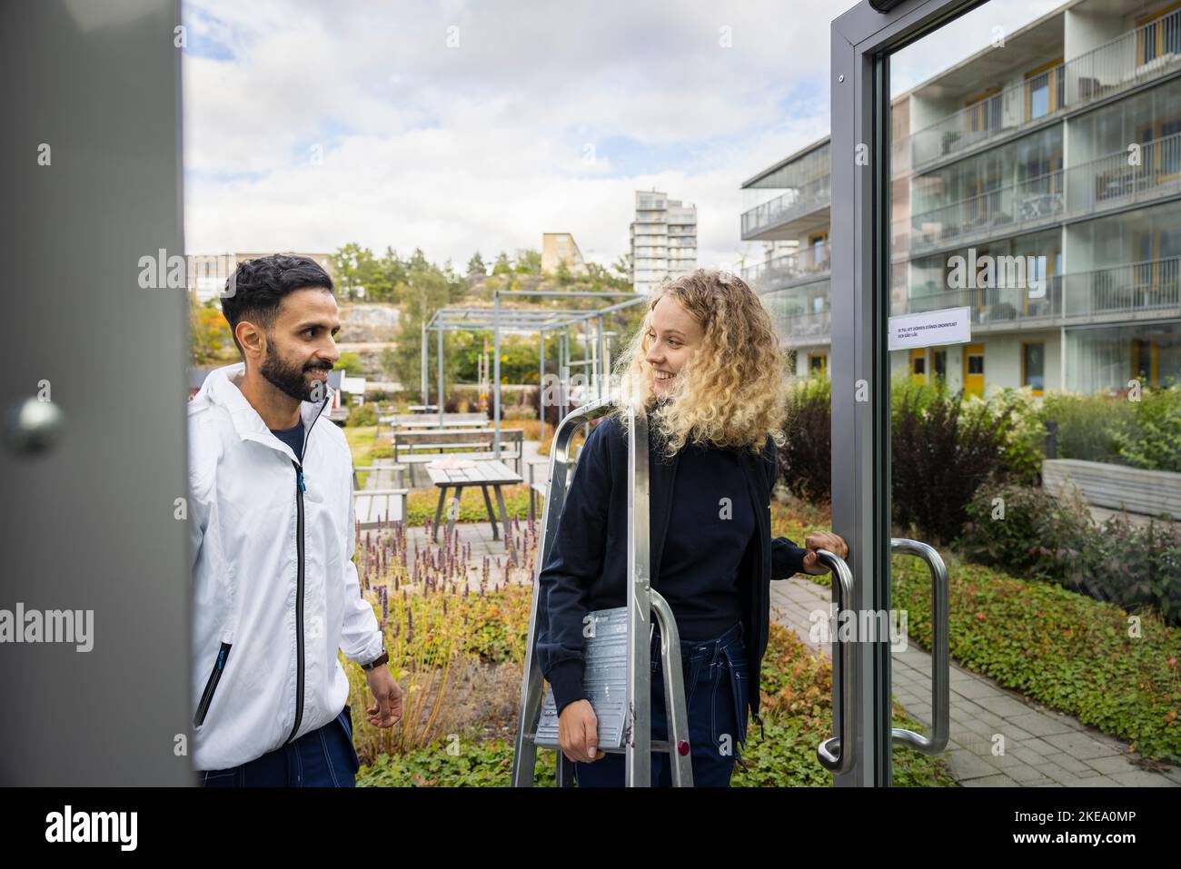 Young technicians entering building with ladder Stock Photo - Alamy