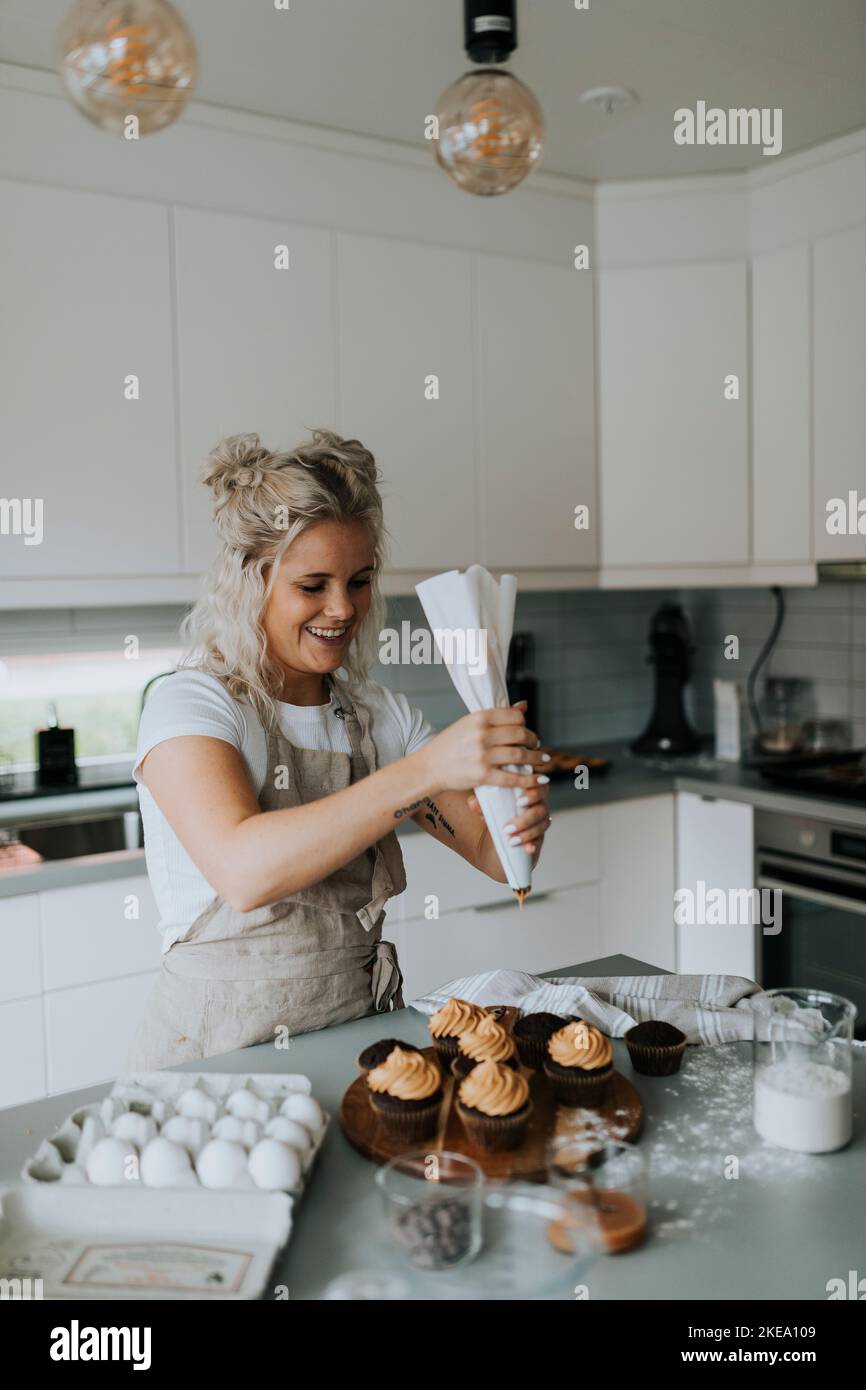 Woman putting icing on cupcakes Stock Photo - Alamy