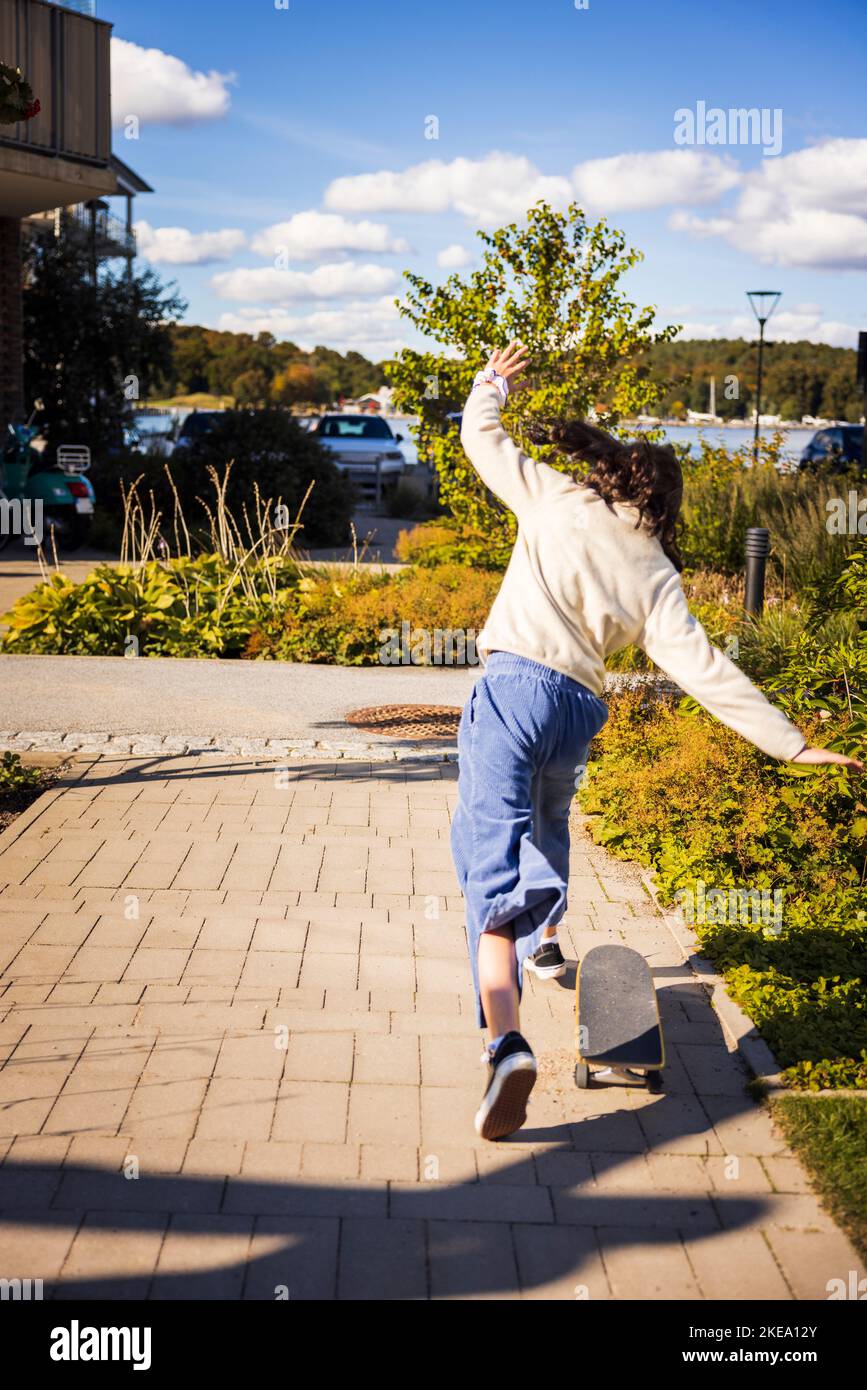 Rear view of girl falling off of skateboard Stock Photo - Alamy