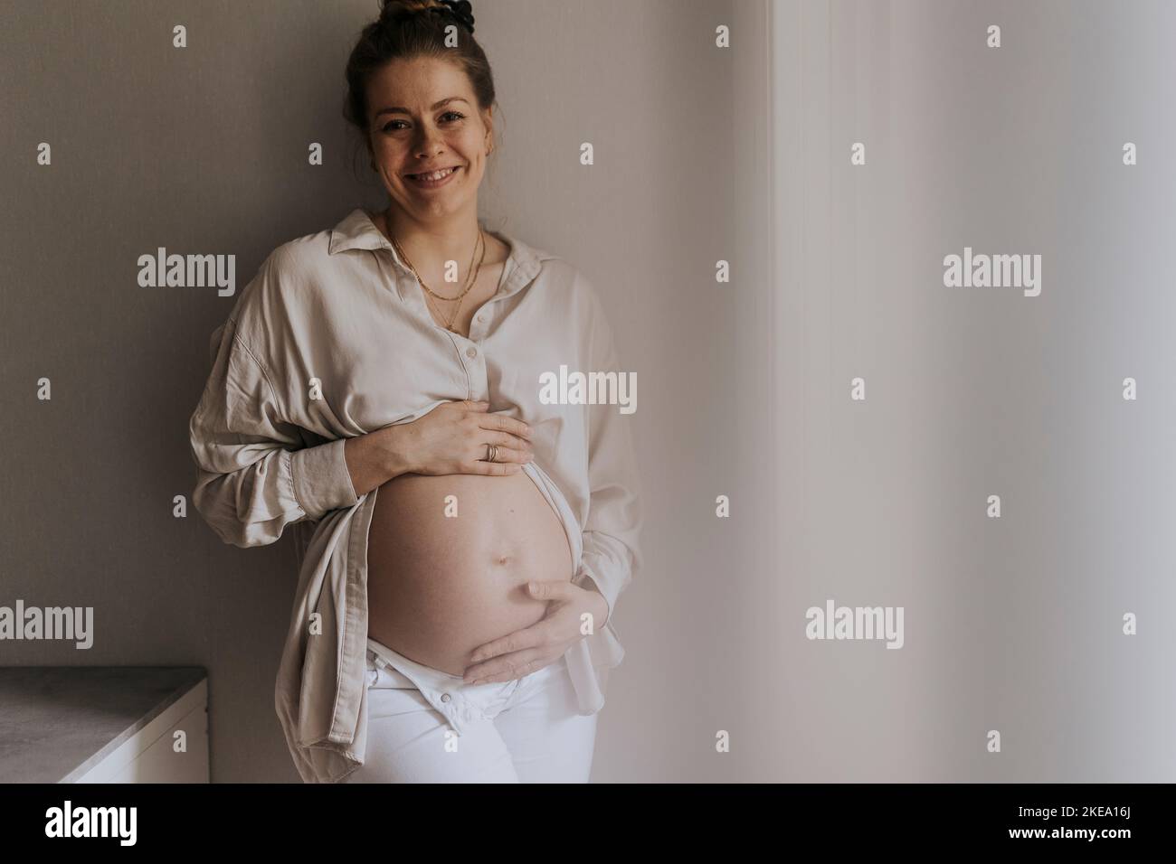 Pregnant woman holding hands on belly Stock Photo - Alamy