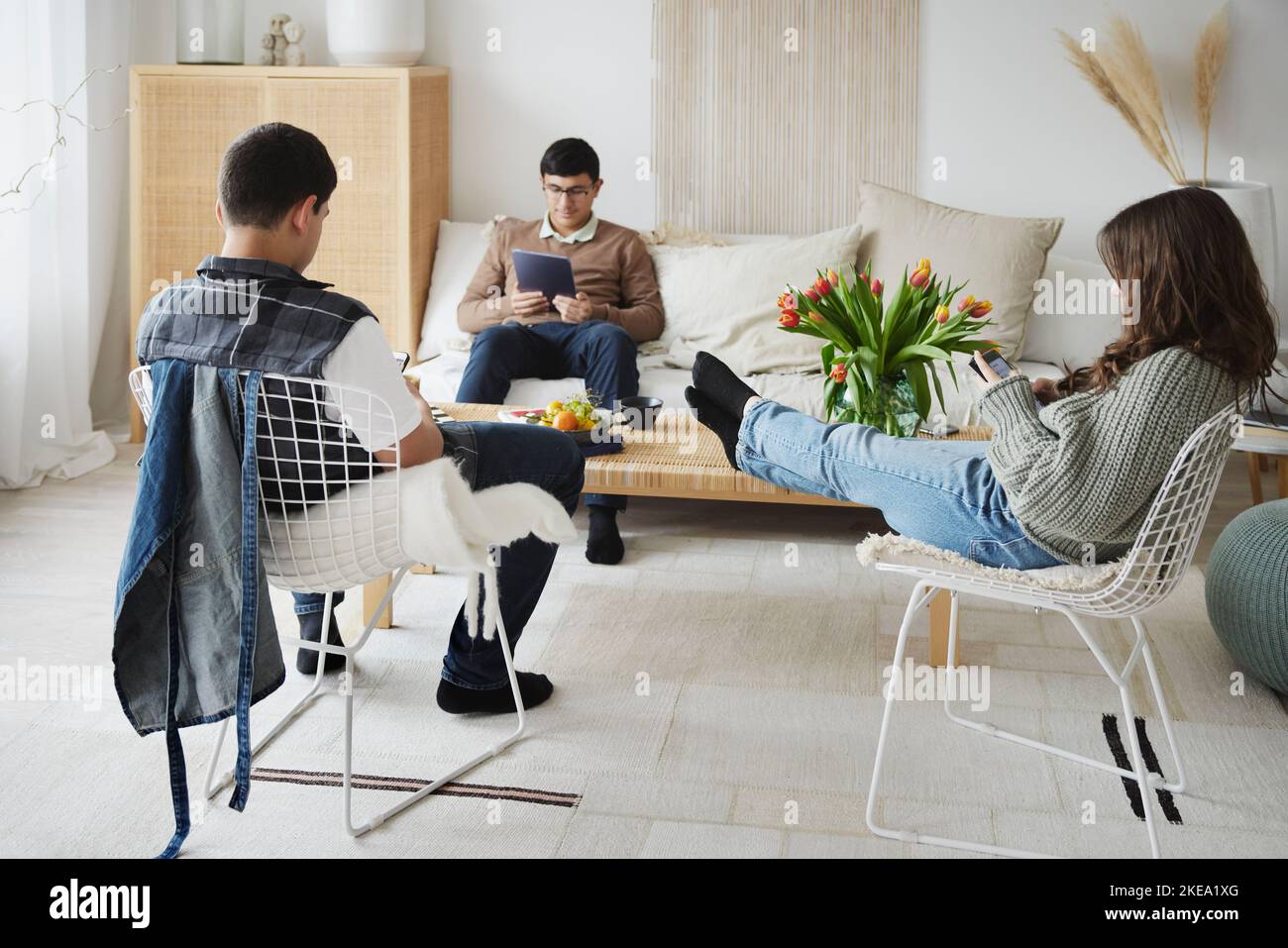 Teenagers sitting in living room and using phones and tablet Stock ...