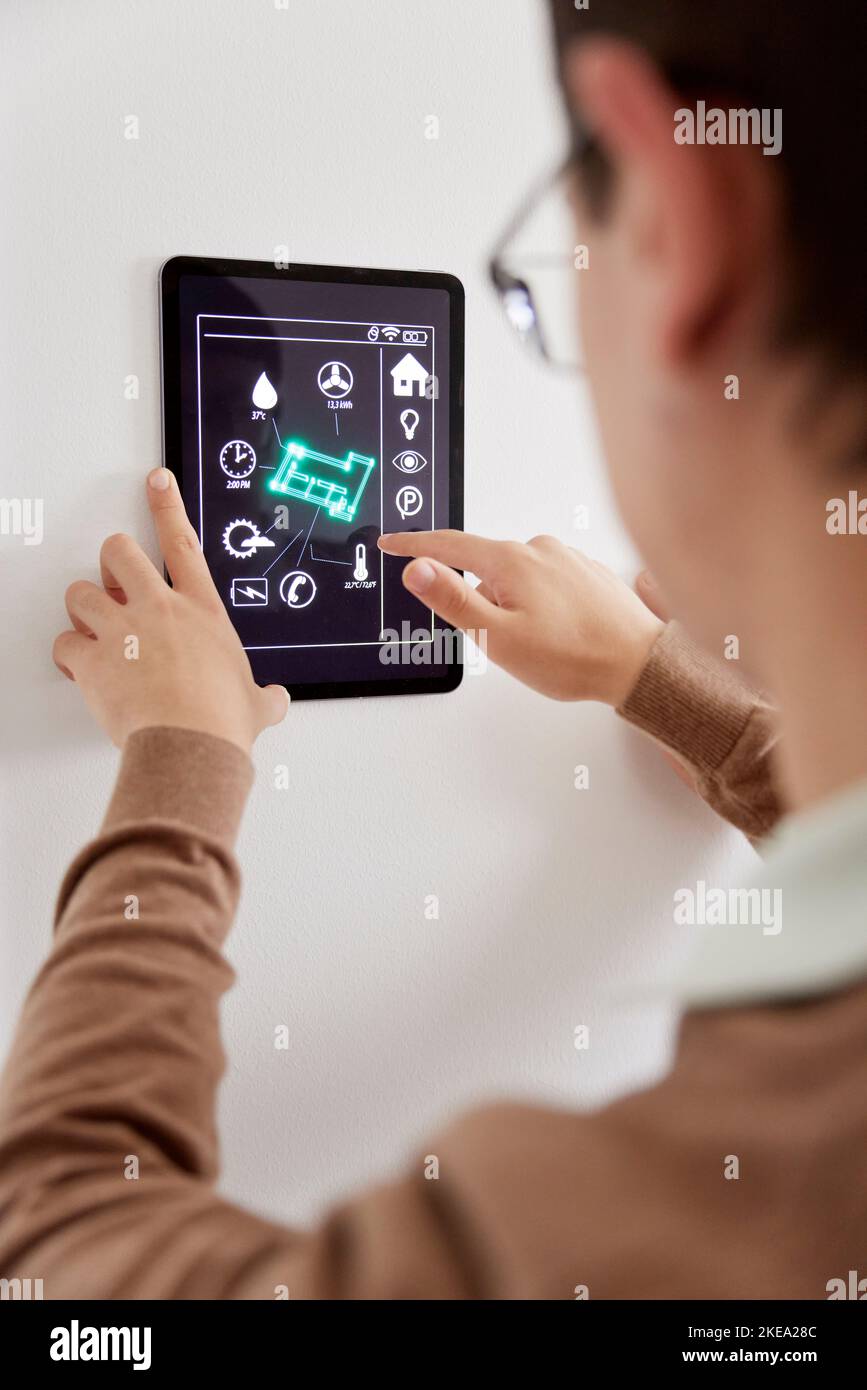 Teenage boy using smart home app on tablet Stock Photo - Alamy