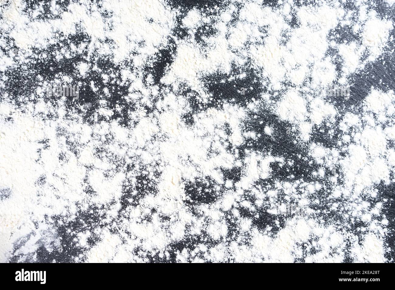 Abstract background of floured black slate surface . Wheat flour spots ...