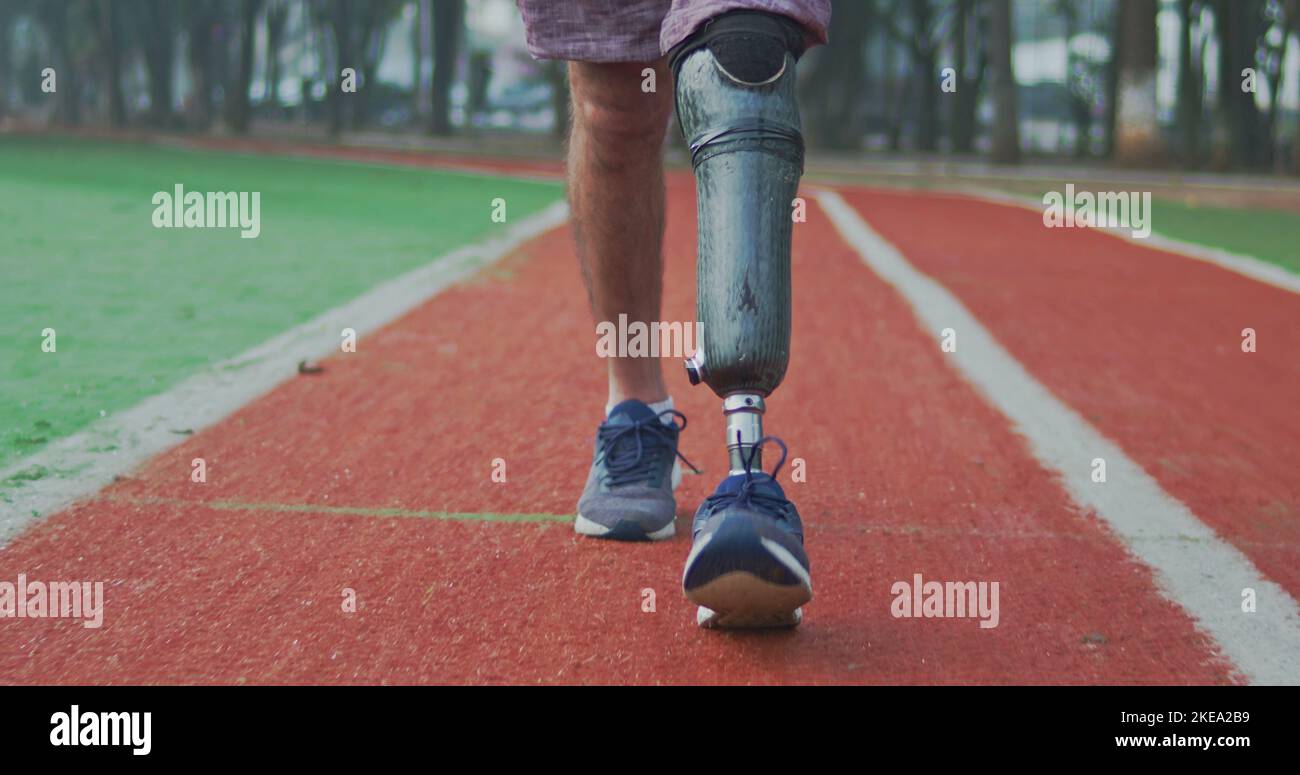 Back view of a disabled athlete man with prosthetic leg walking on ...