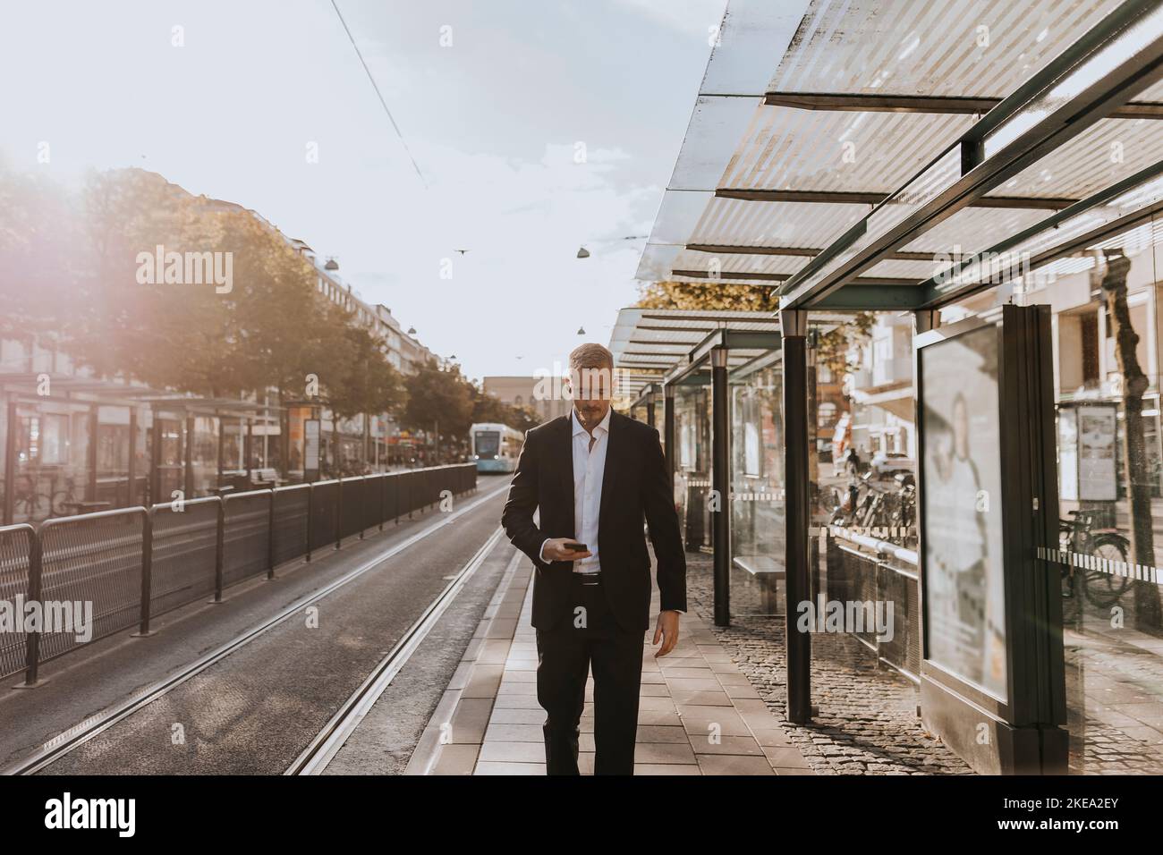 Businessman walking and using cell phone Stock Photo - Alamy