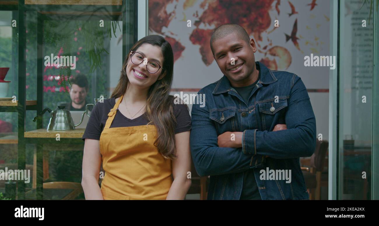 Two diverse Brazilian hispanic employees of coffee shop portrait faces ...