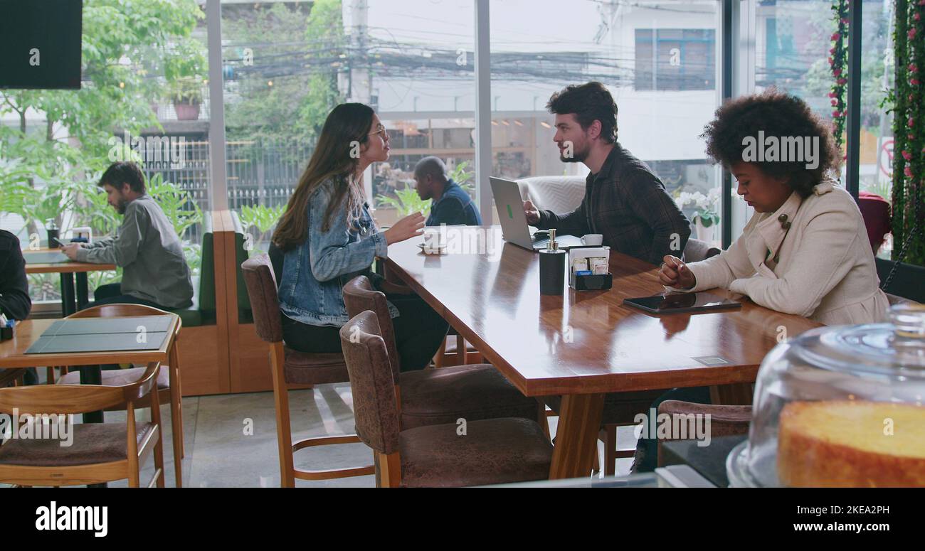 Group of people inside coffee shop. Female friend handing espresso to ...