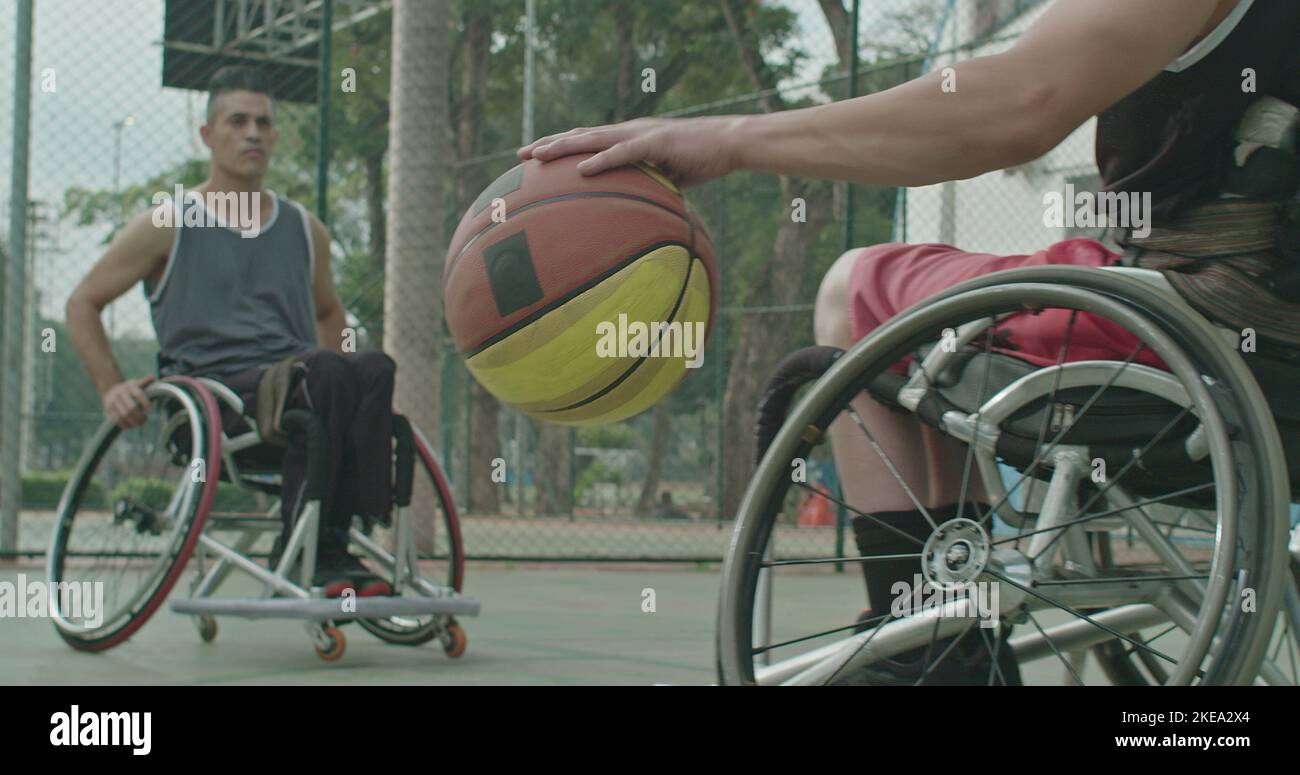 A paraplegic male athlete receiving ball from colleague outdoors. Two ...