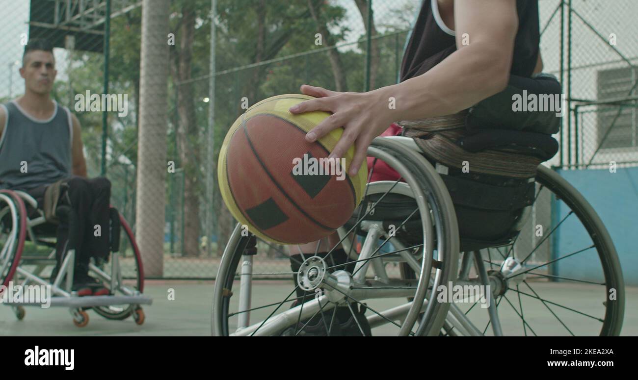 A paraplegic male athlete receiving ball from colleague outdoors. Two ...