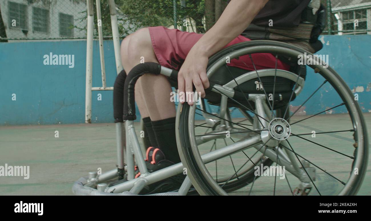 A paraplegic male athlete playing basketball outside. One male disabled ...
