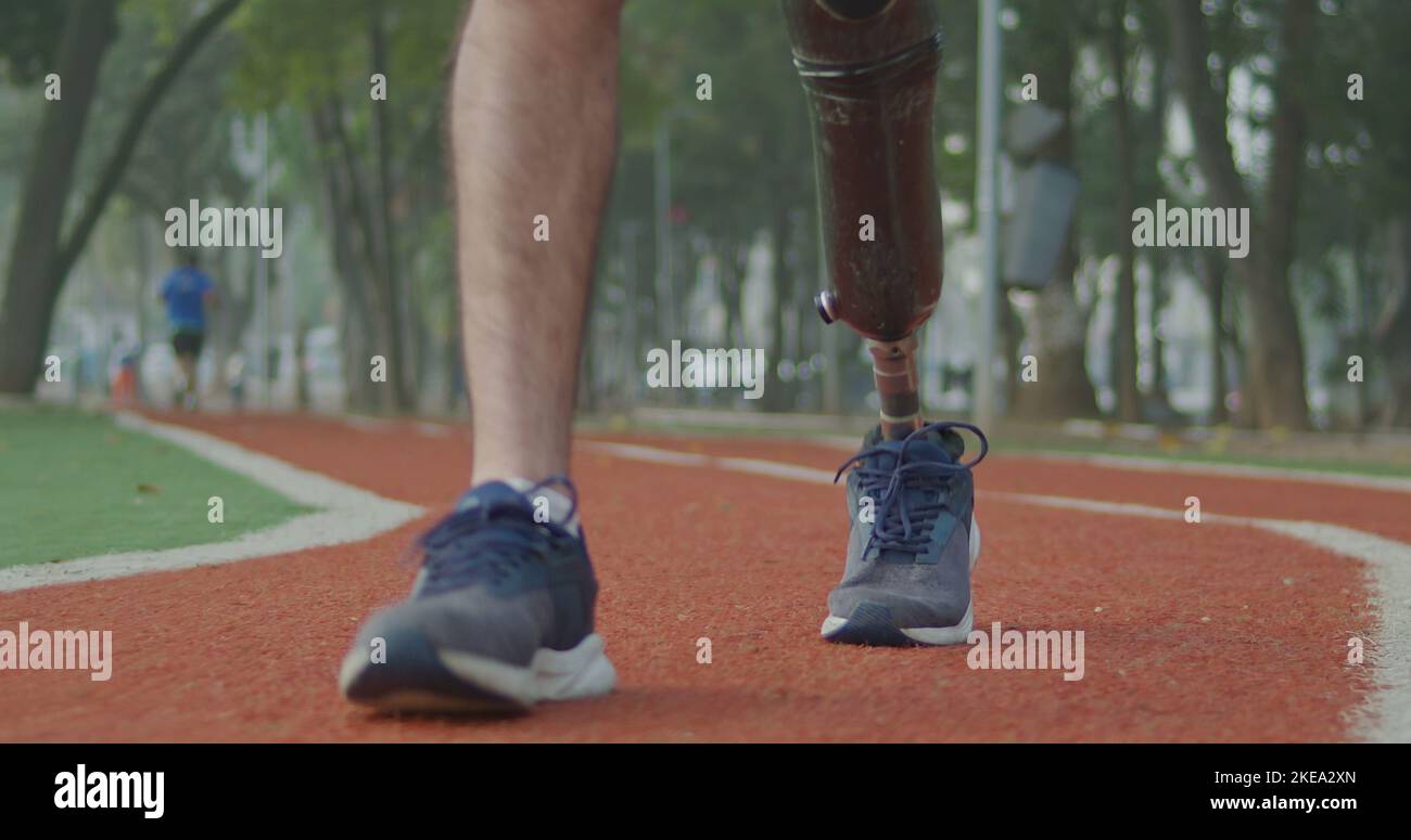 Front view of a disabled athlete walks outdoors with prosthetic leg ...
