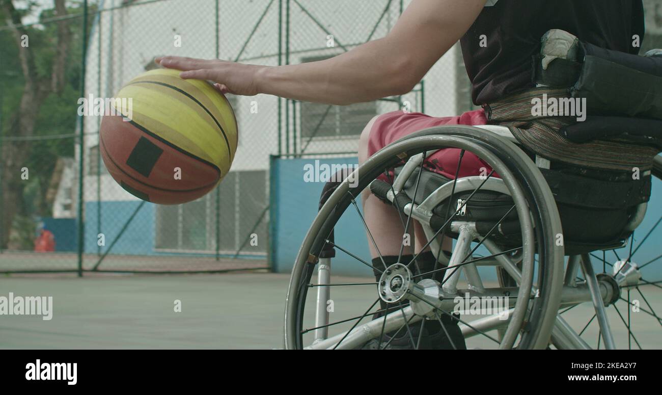 A paraplegic male athlete receiving ball from colleague outdoors. Two ...