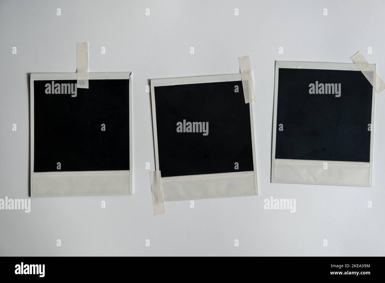 Collection of blank photo frames taped on white wall. Set of photos ...