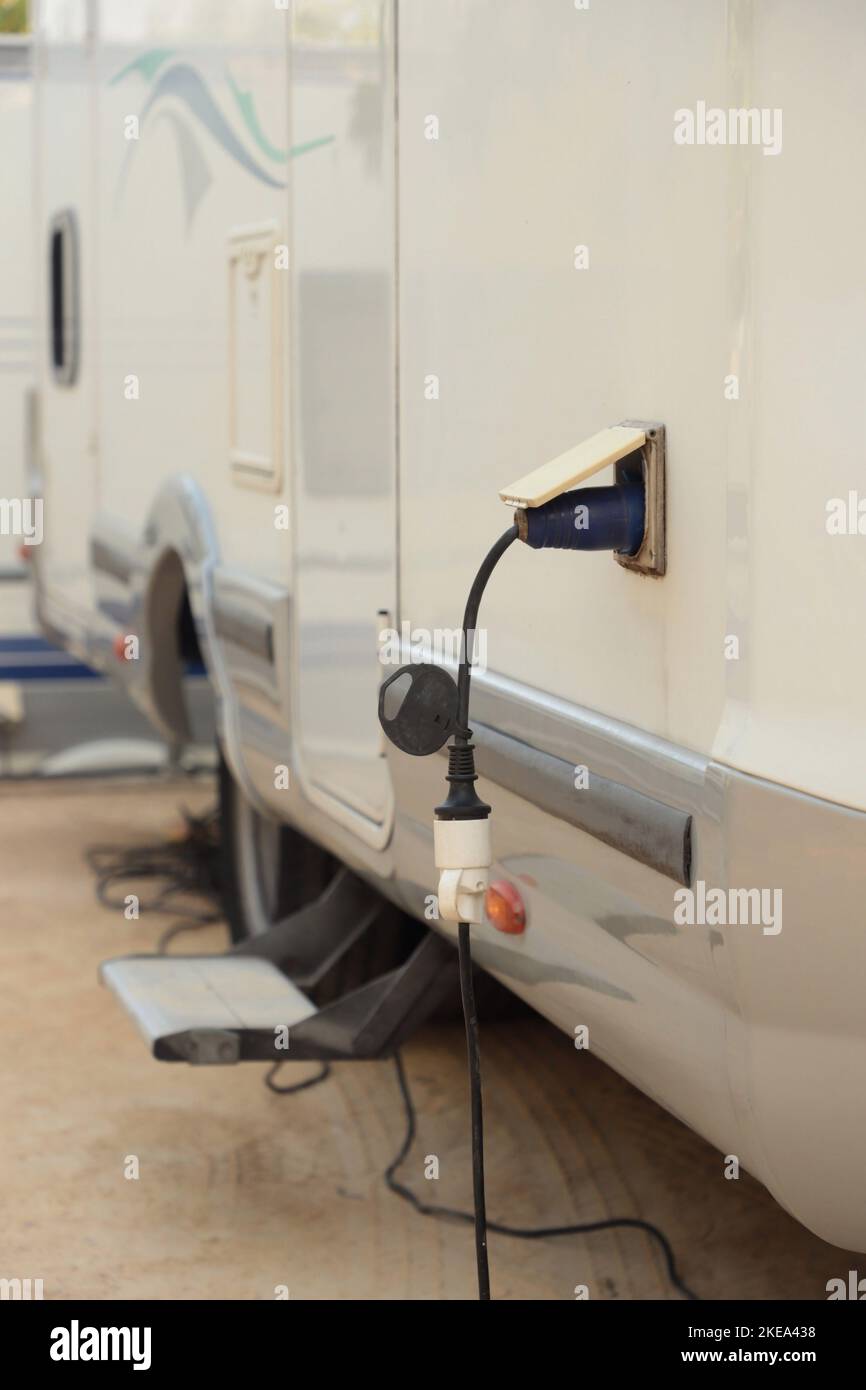 A vertical shot of a camping motorhome connected to electricity through ...