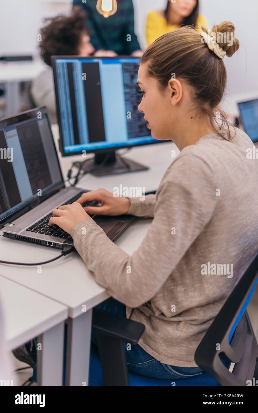 Picture from behind of a female employee sitting at her desk and ...