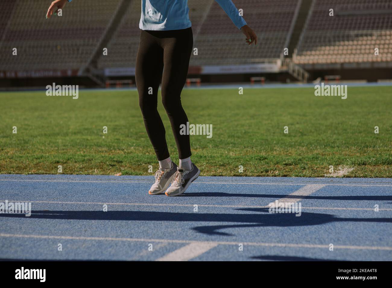 A young girl is training alone at the stadium. She is jumping ...