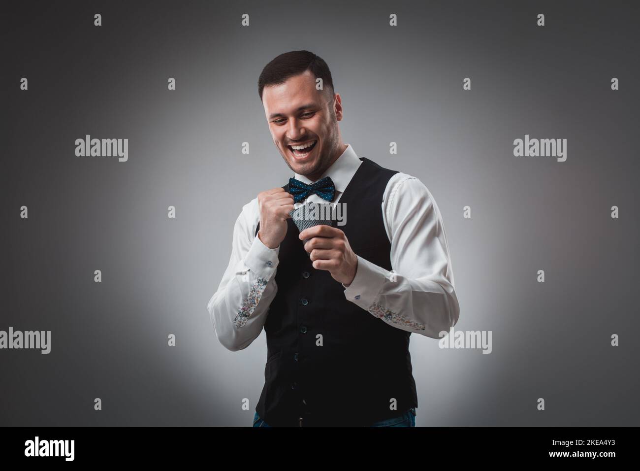 Young man in shirt and waistcoat watch his poker cards, studio shot ...